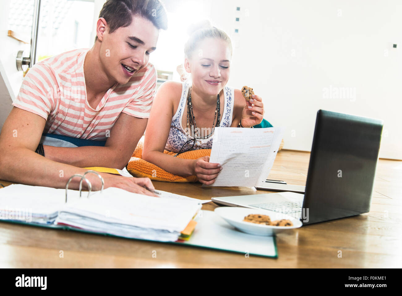 Two students lying on wooden floor learning Stock Photo - Alamy