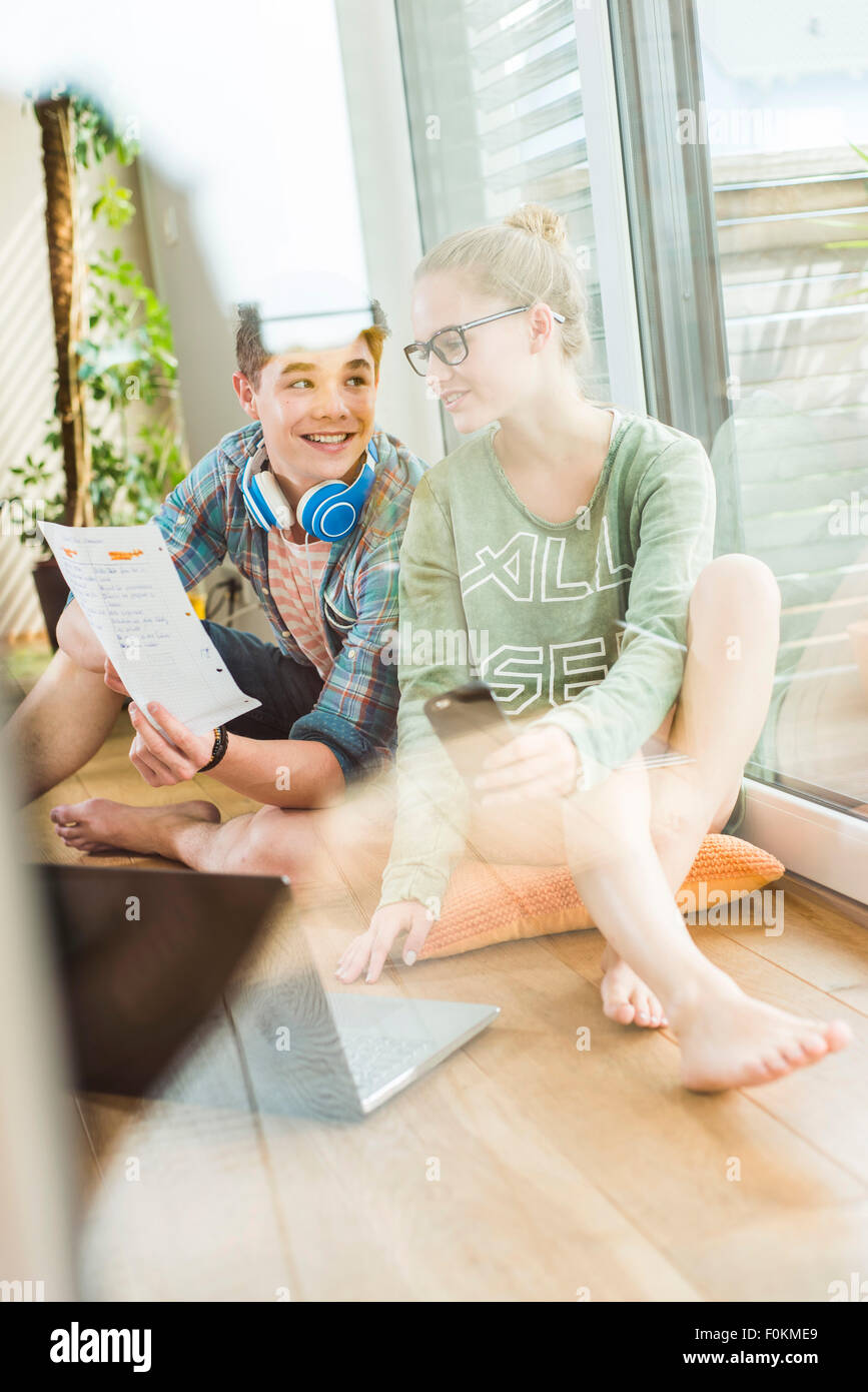 Two students sitting on wooden floor learning Stock Photo - Alamy