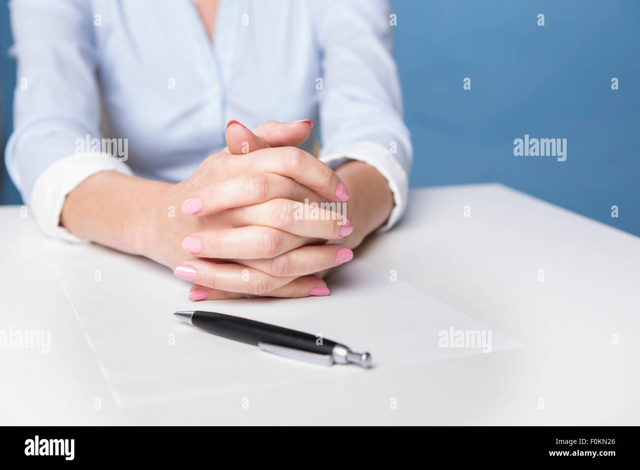 Woman's folded hands on a sheet of paper Stock Photo - Alamy