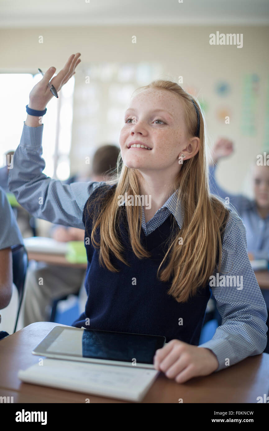 Schoolgirl in classroom raising her hand Stock Photo - Alamy