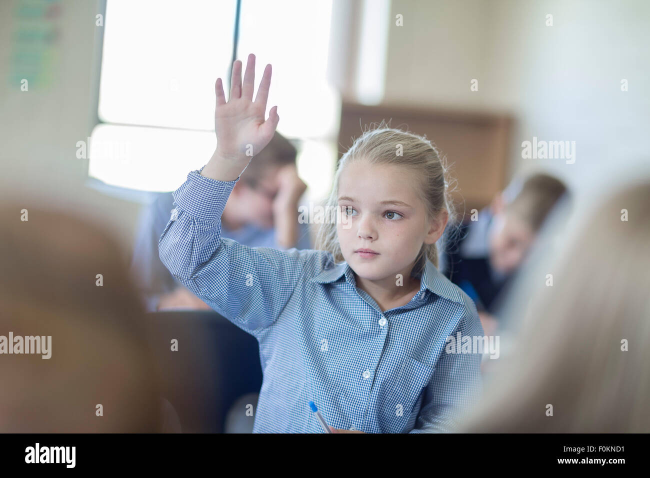 Schoolgirl in classroom raising her hand Stock Photo - Alamy