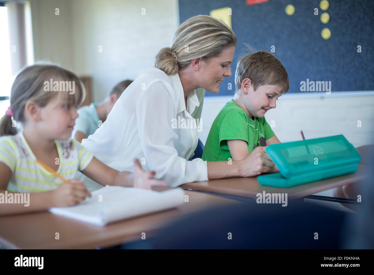 Teacher helping schoolboy in classroom Stock Photo - Alamy