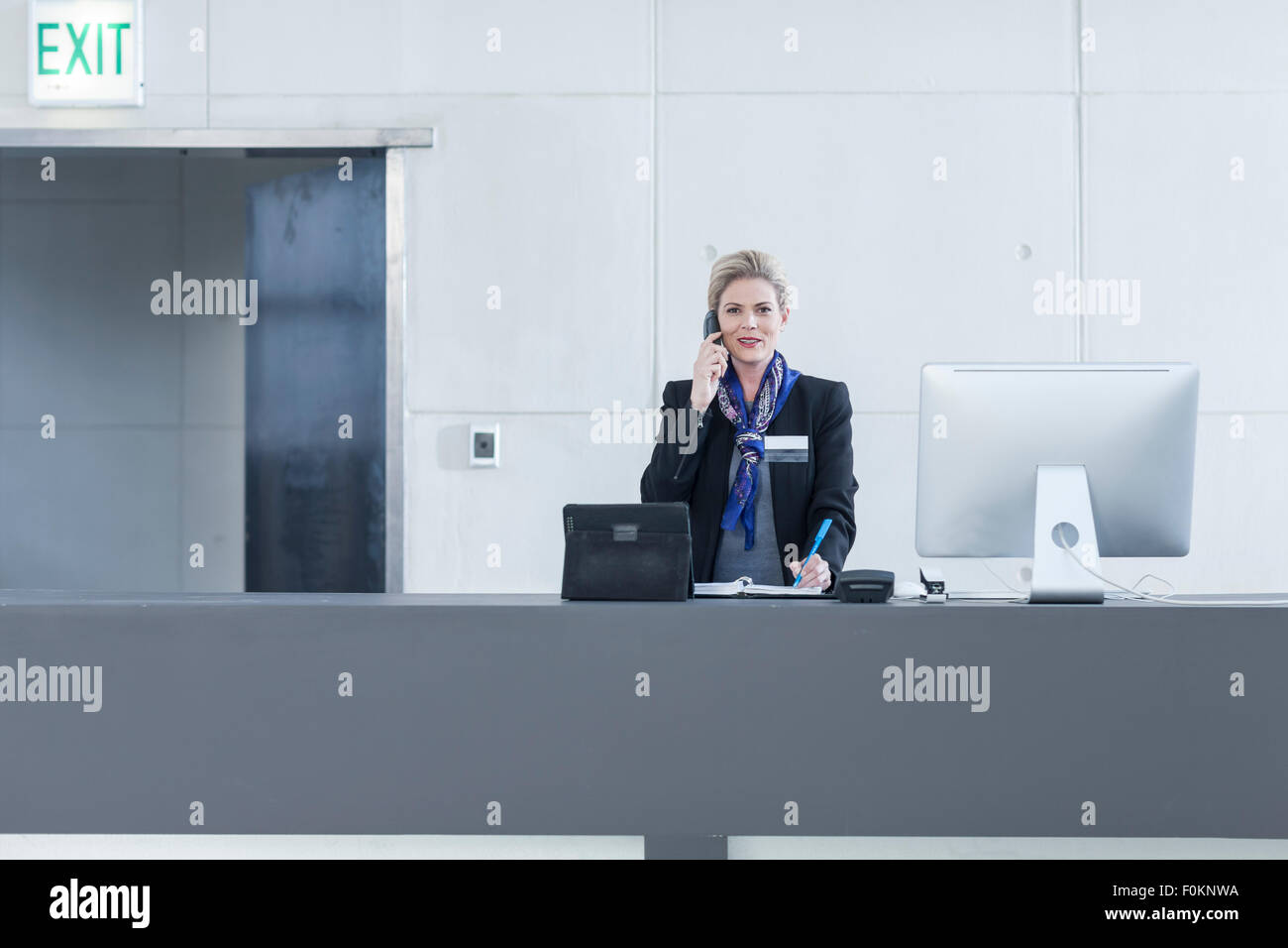Woman behind reception desk in hotel lobby on the phone Stock Photo - Alamy