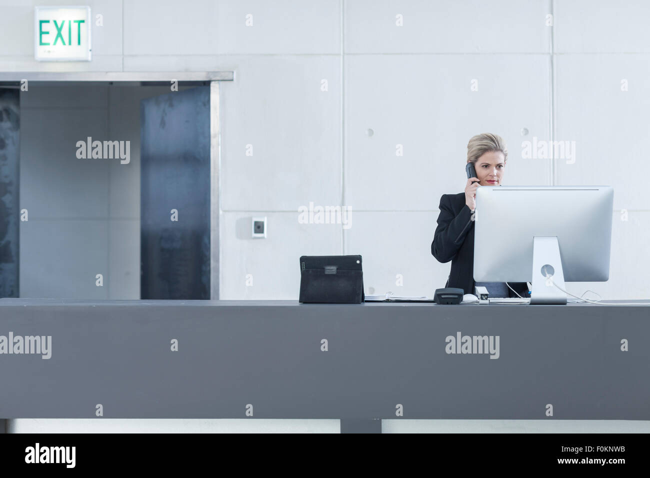 Woman behind reception desk in hotel lobby on the phone Stock Photo - Alamy