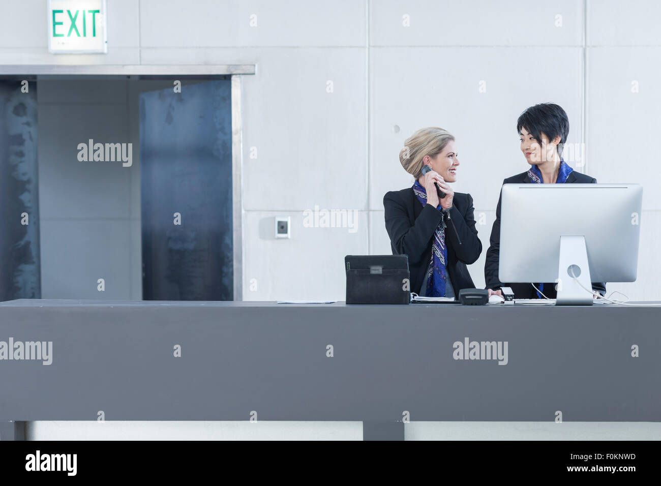 Two women behind reception desk in hotel lobby Stock Photo - Alamy