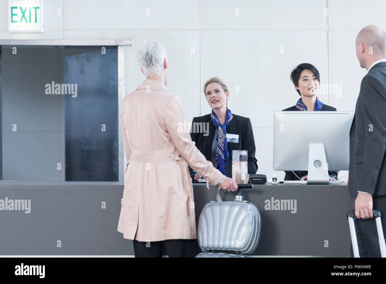 Two women behind reception desk in hotel lobby helping guests Stock ...