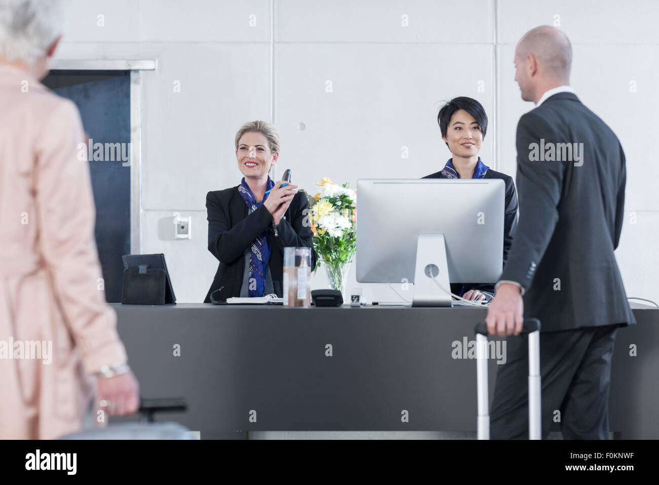 Two women behind reception desk in hotel lobby helping guests Stock ...