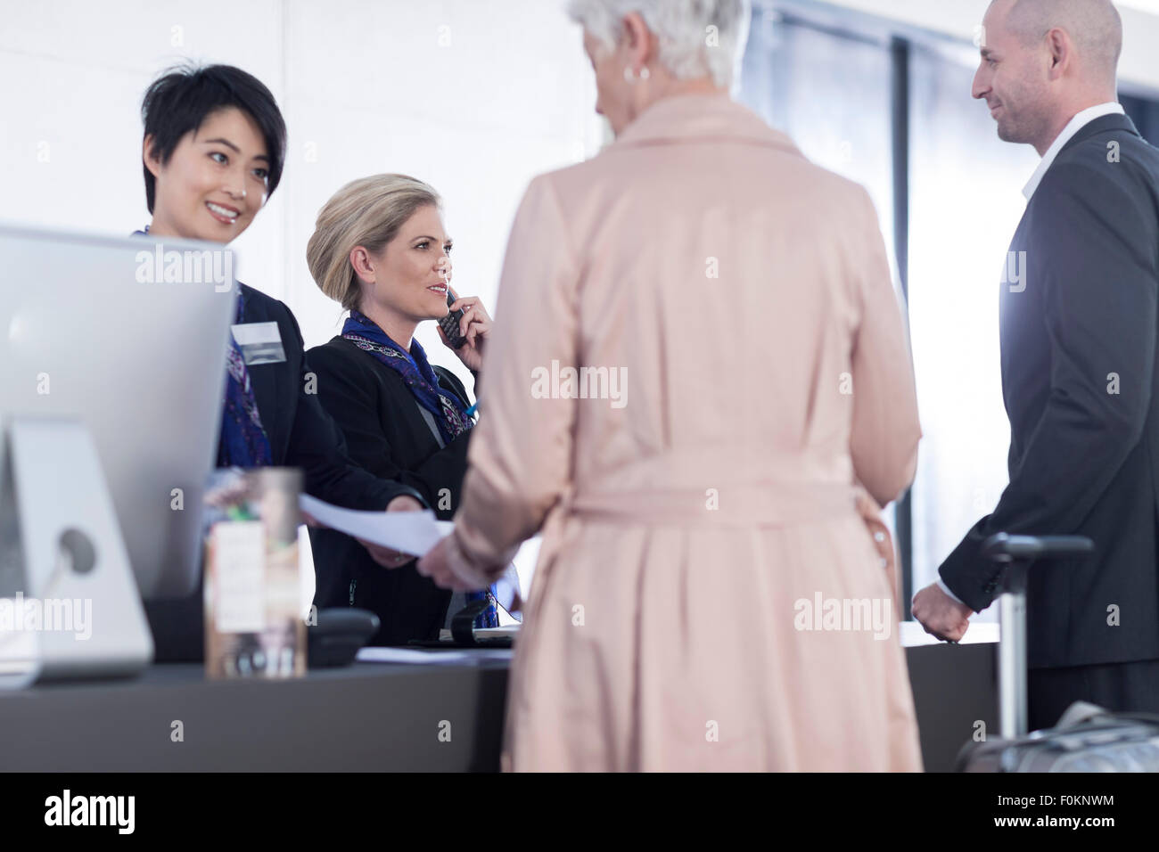 Two women behind reception desk in hotel lobby helping guests Stock ...
