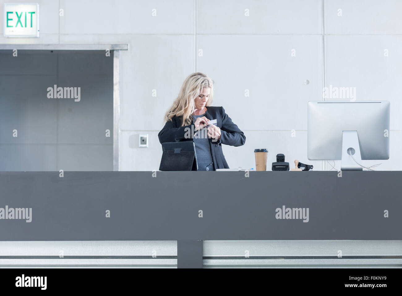 Woman behind reception desk in hotel lobby attaching nameplate Stock ...