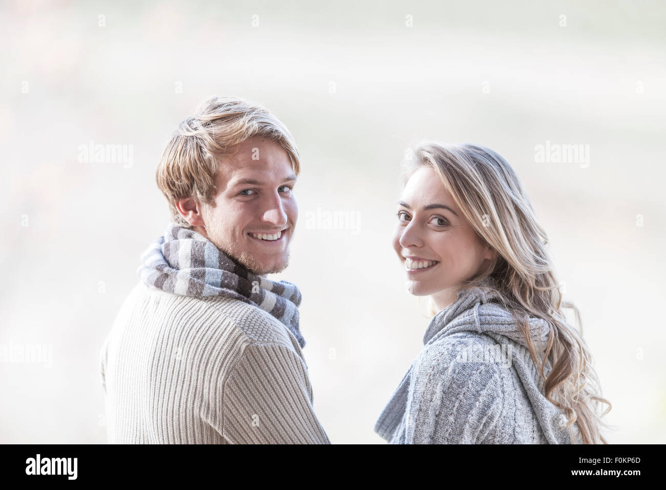 Portrait of smiling young couple looking over their shoulders Stock ...
