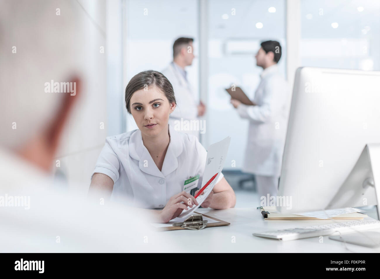 Nurse helping patient at clinic reception Stock Photo - Alamy