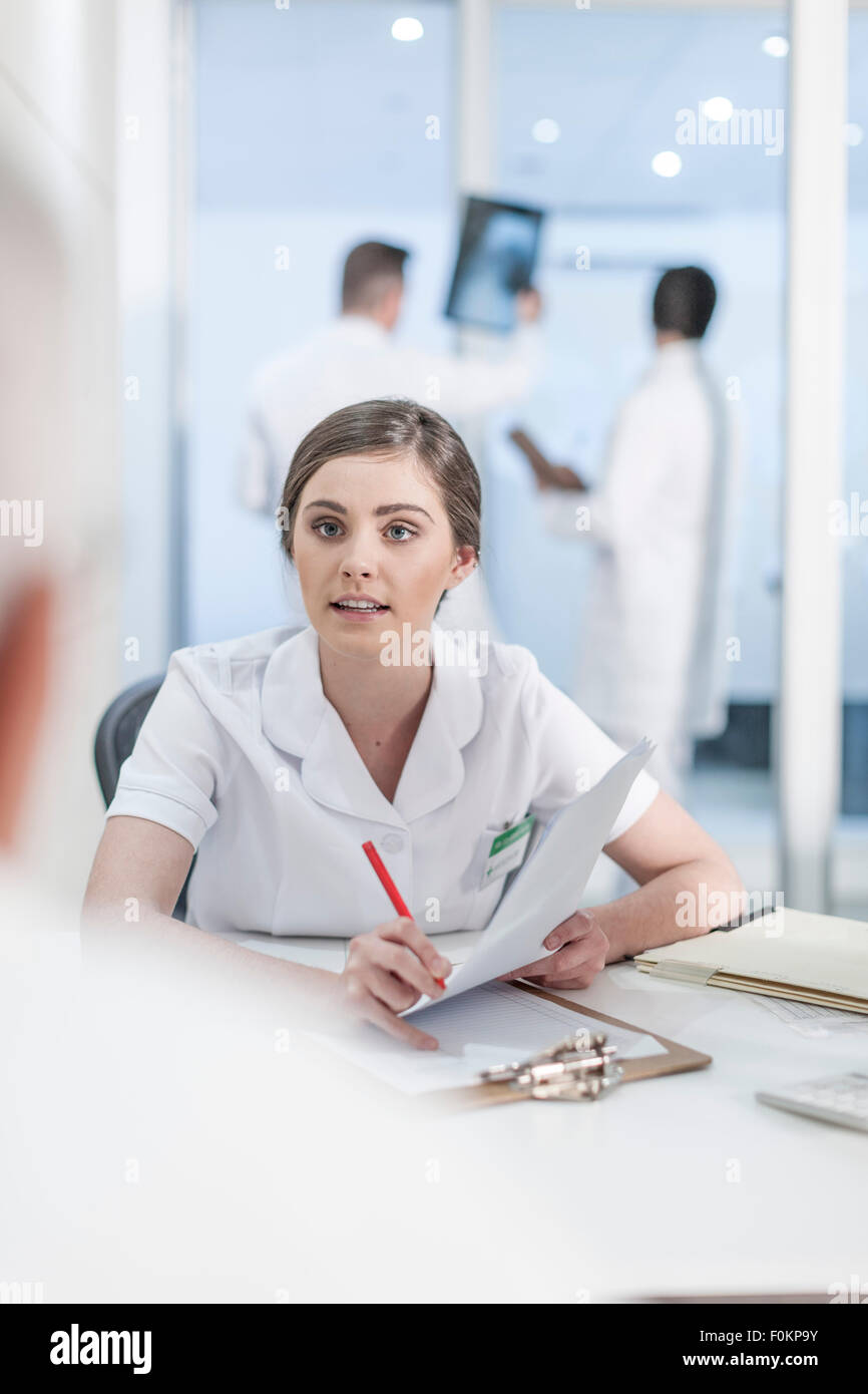 Nurse helping patient at clinic reception Stock Photo - Alamy
