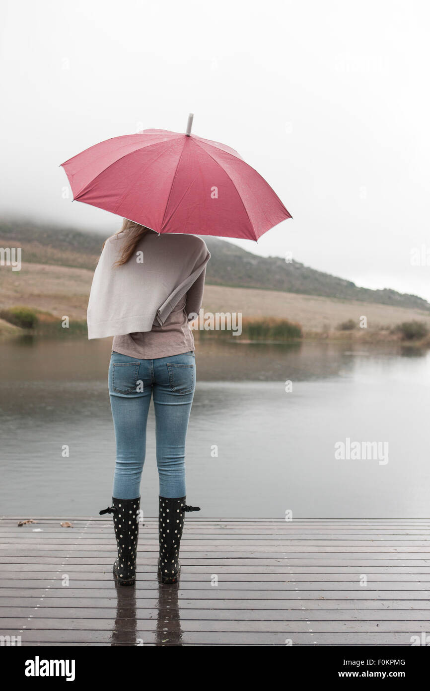 Back view of young woman standing in the rain with umbrella Stock Photo ...