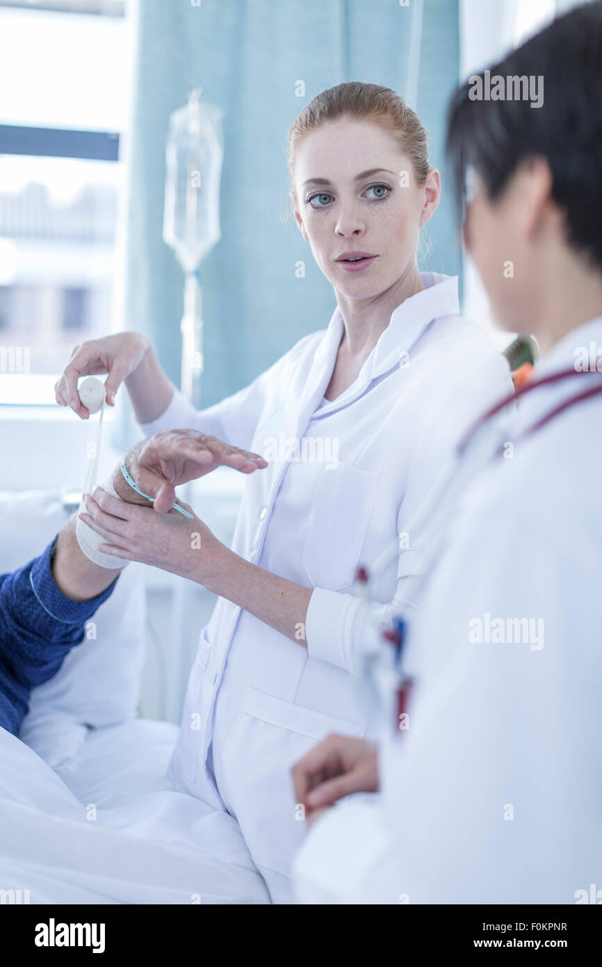 Portrait of a nurse bandaging arm of a patient in the hospital Stock ...