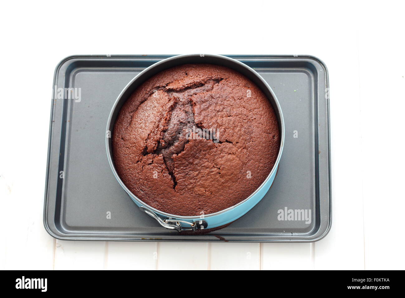Freshly baked chocolate cake in a baking tin with a crack on the cake ...