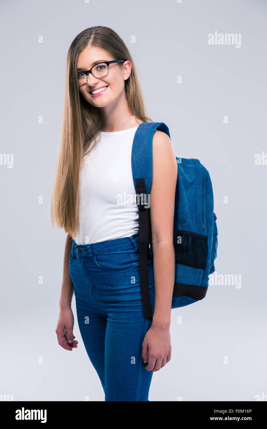 Portrait of a cheerful female teenager with backpack standing isolated ...