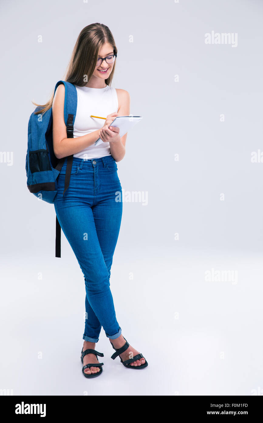 Full length portrait of a smiling female teenager writing notes in ...