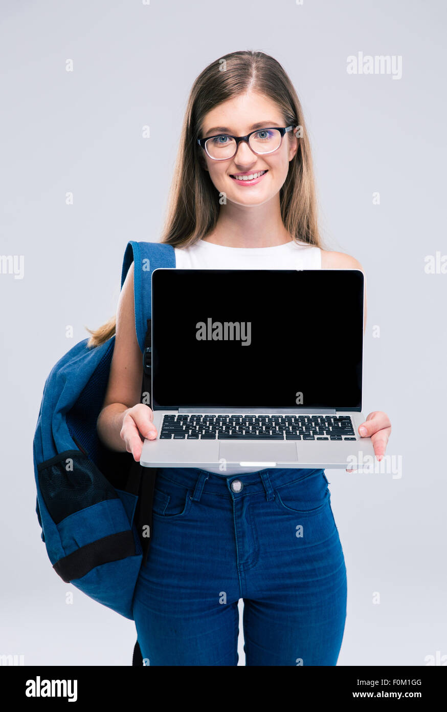 Portrait of a smiling female teenager showing blank laptop computer ...