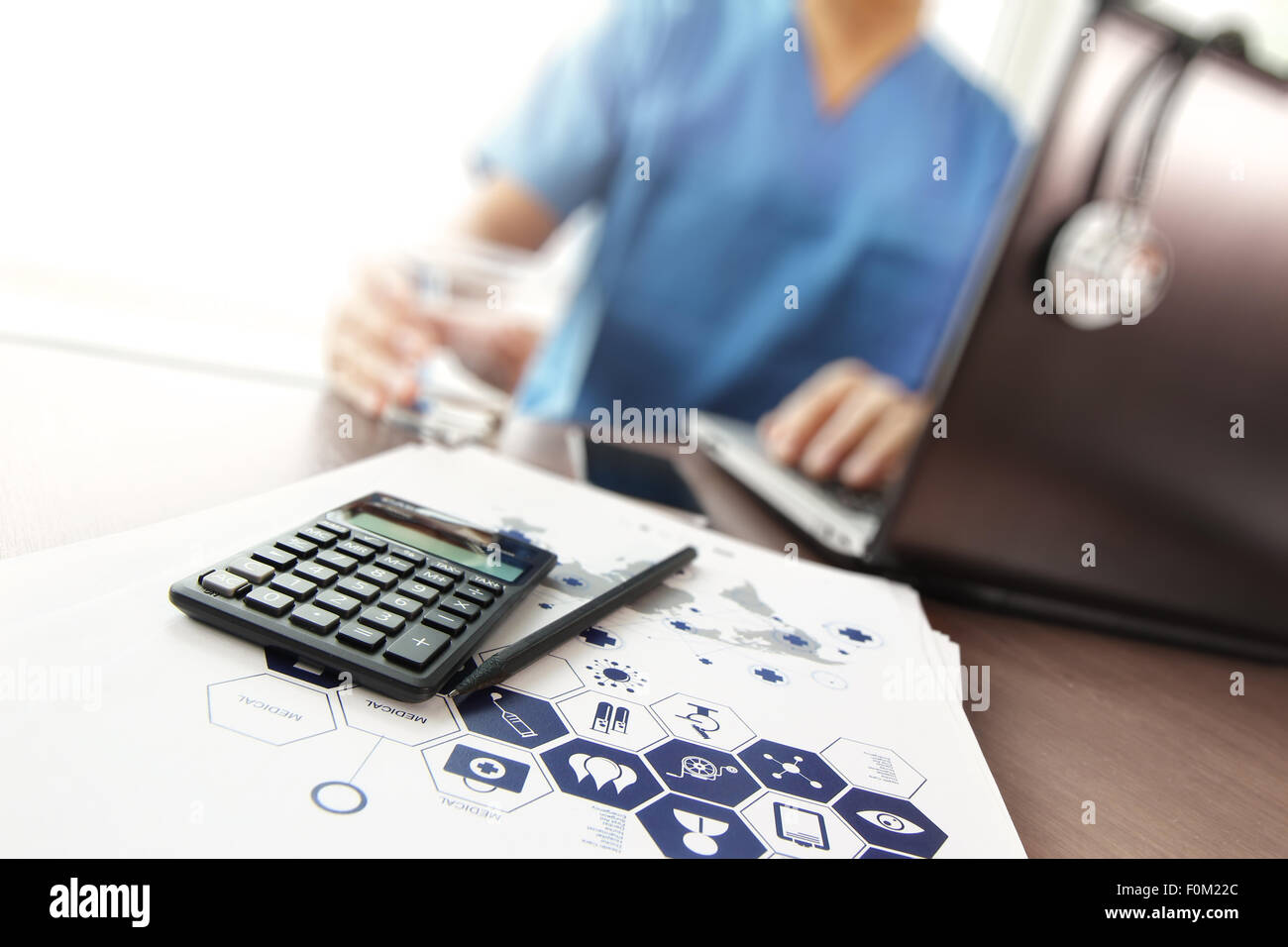 Doctor working with laptop computer and calculater in medical workspace ...