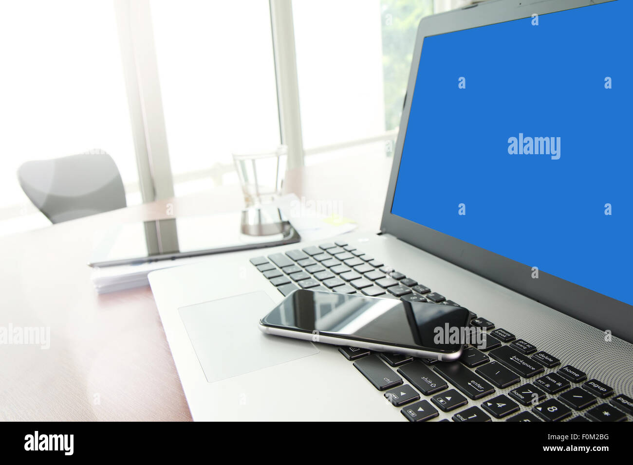 Office workplace with blank screen laptop computer and smart phone and ...