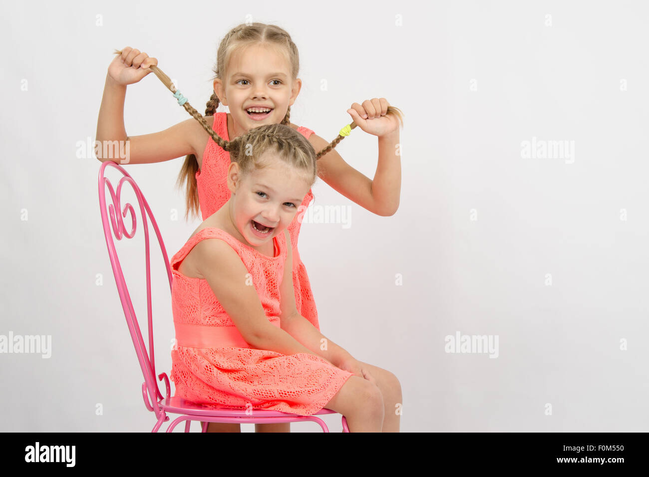 Two girls sisters in the same clothes having fun playing with each ...