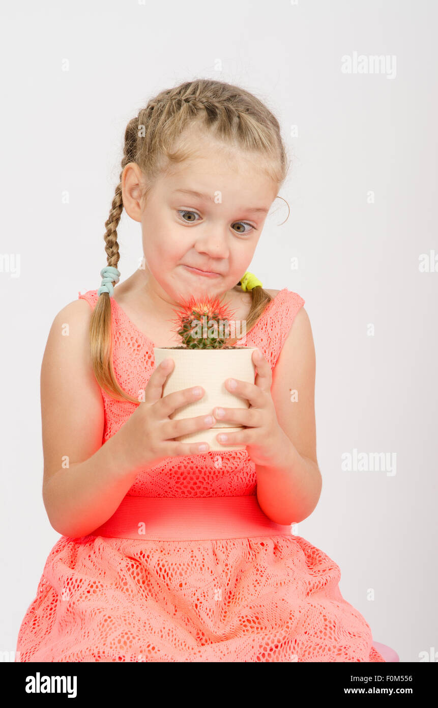 Four Year Girl Stands With A Cactus In A Pot Isolated On A Light