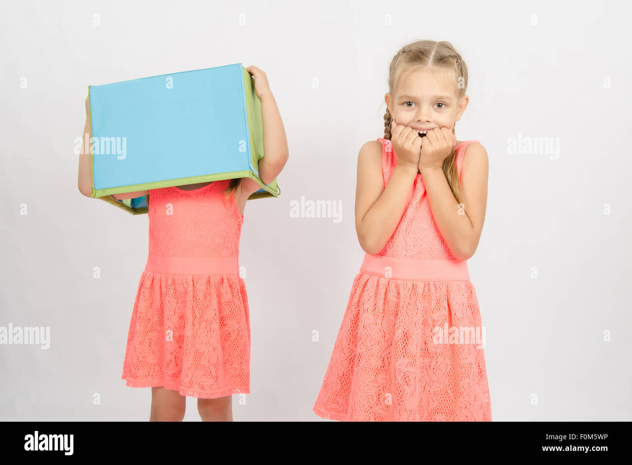Two girls wearing a box on his head, isolated on a light background ...