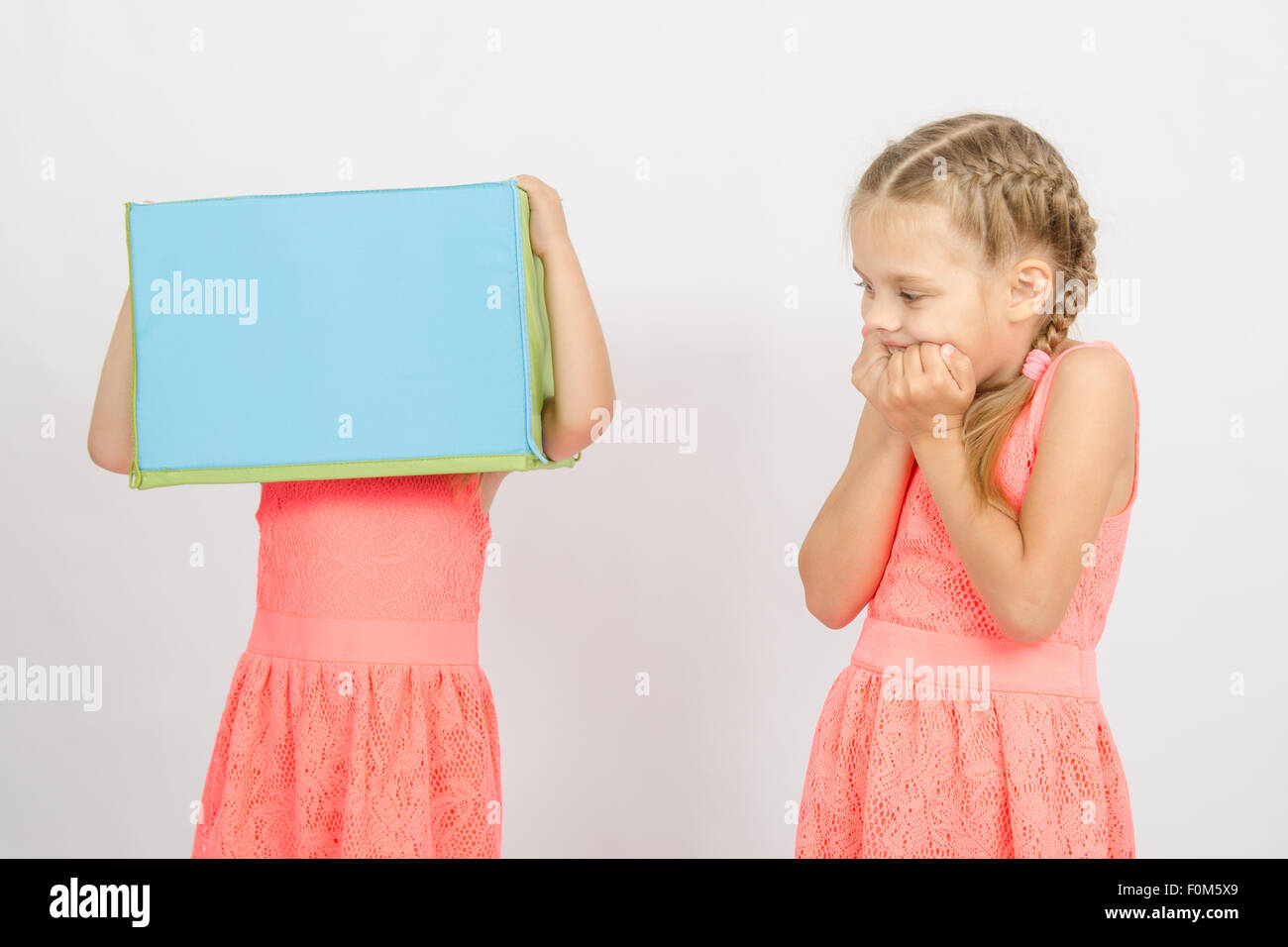 Two girls wearing a box on his head, isolated on a light background ...