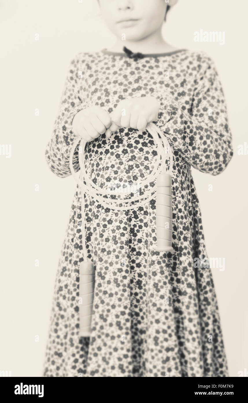 Portrait of little girl in dress with flowers. She is holding a jump ...