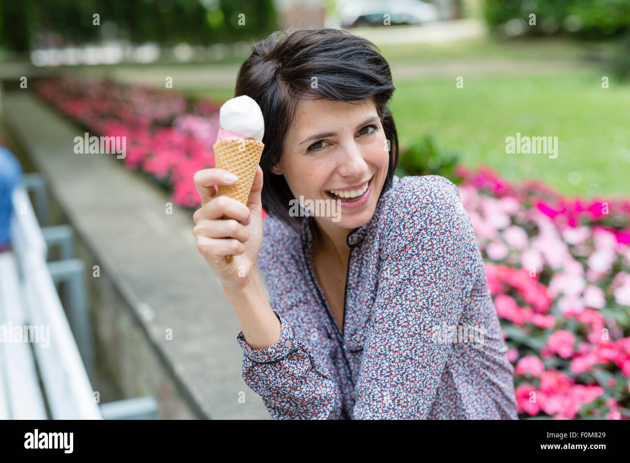 Smiling woman sitting on bench and eating ice cream Stock Photo - Alamy