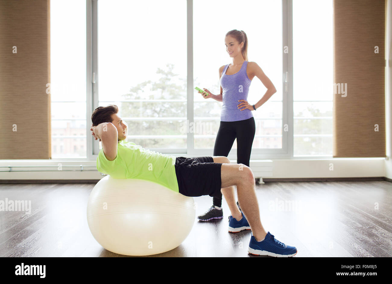 smiling man and woman with exercise ball in gym Stock Photo - Alamy