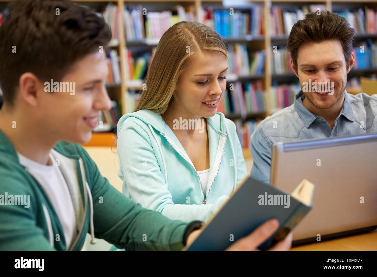 happy students with laptop and book at library Stock Photo - Alamy