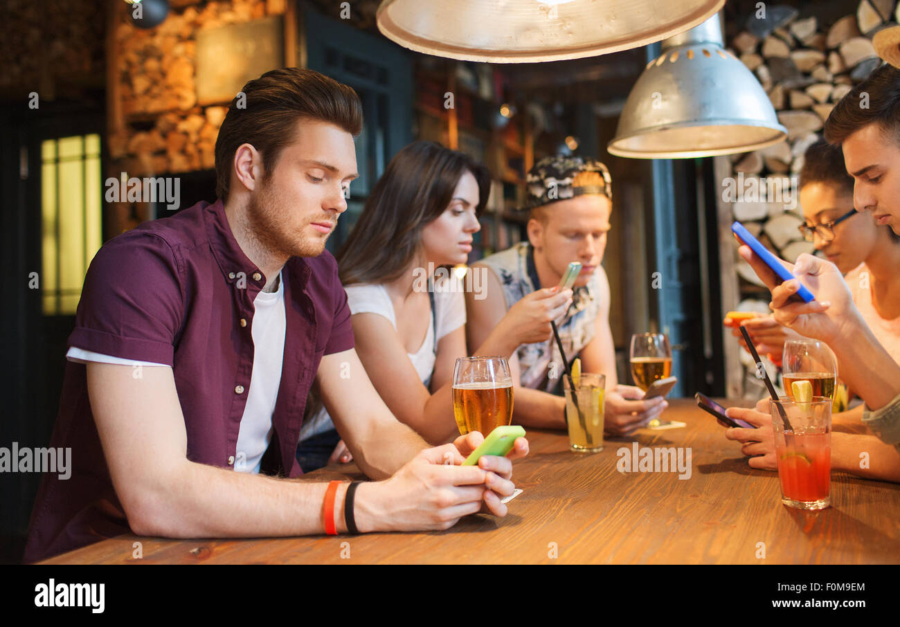 friends with smartphones and drinks at bar Stock Photo - Alamy