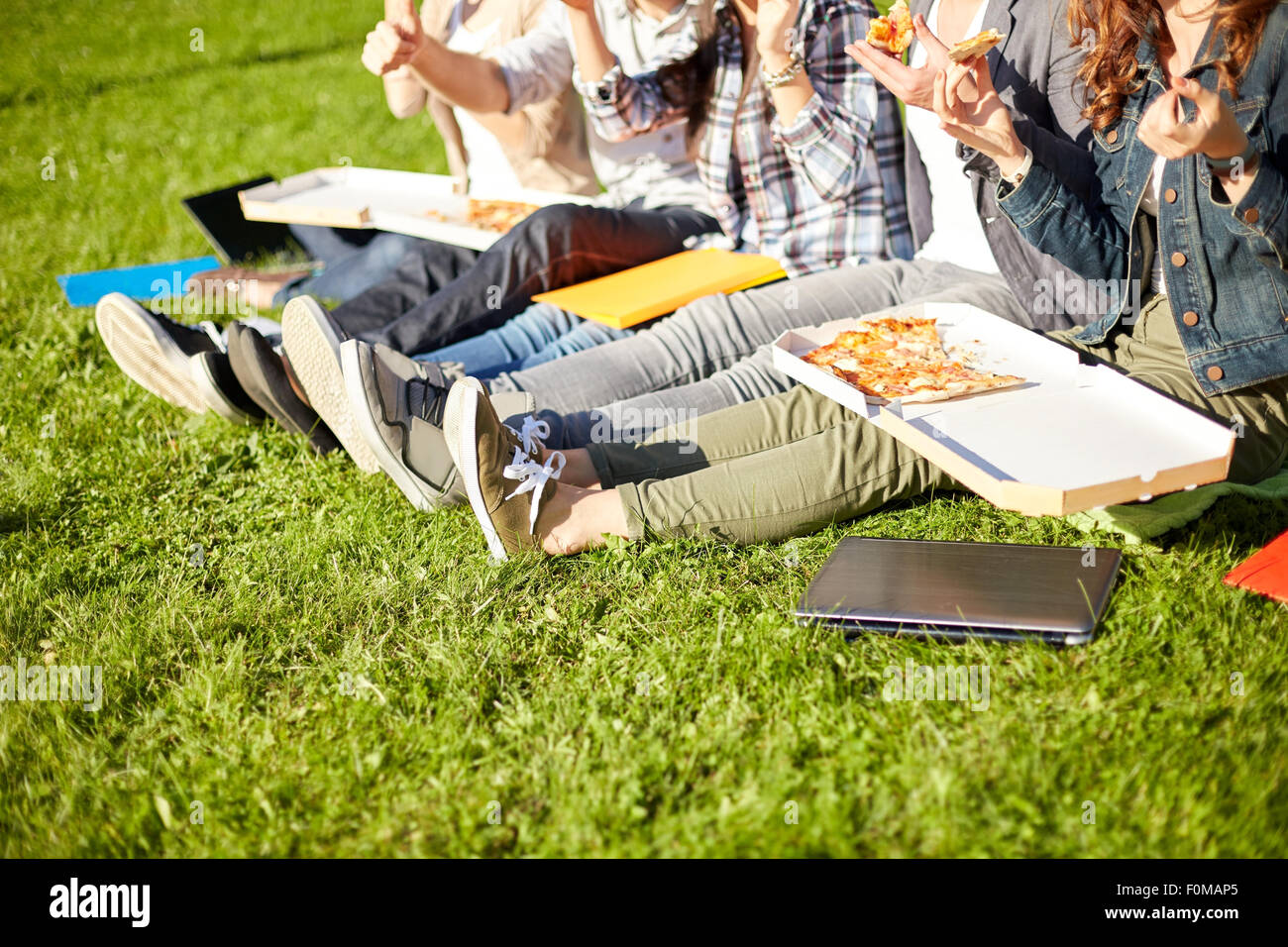 close up of teenage students eating pizza on grass Stock Photo - Alamy
