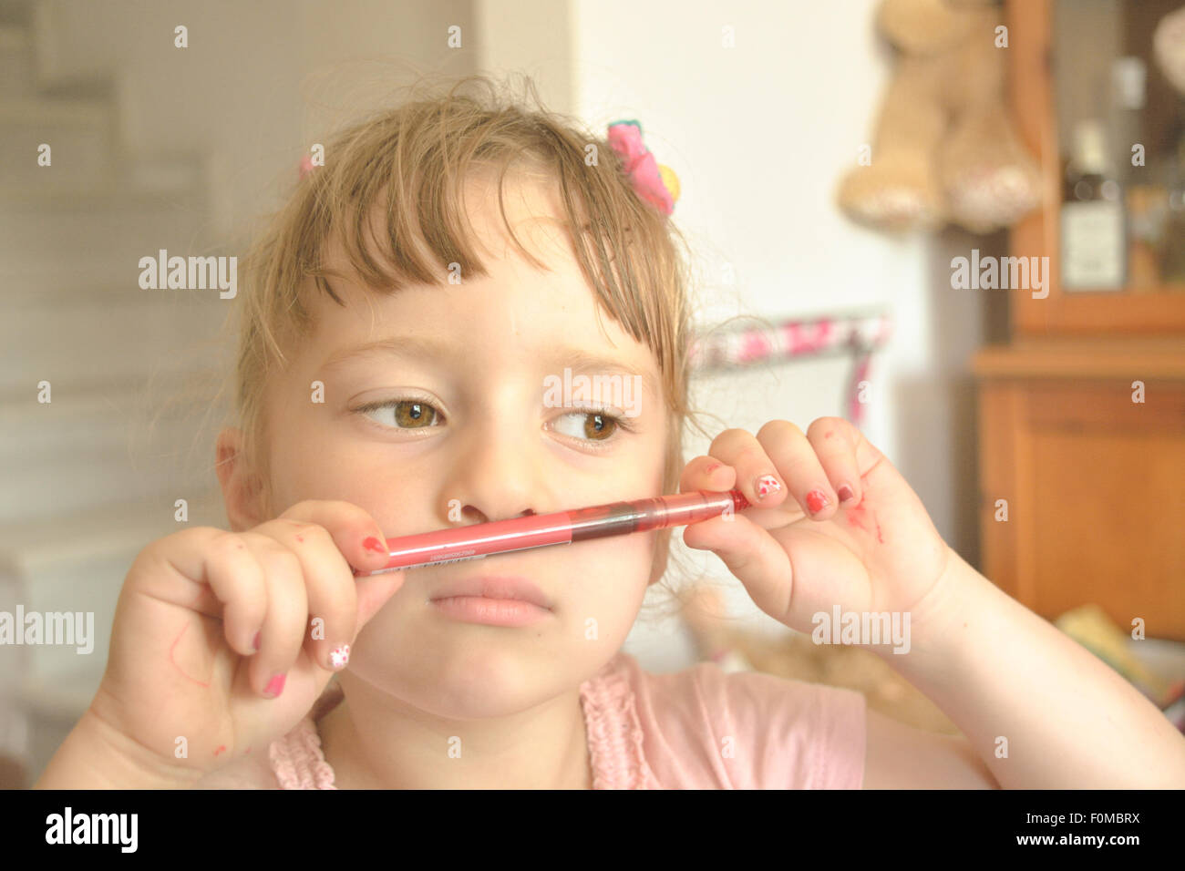 A little girl with a pen thinking Stock Photo - Alamy