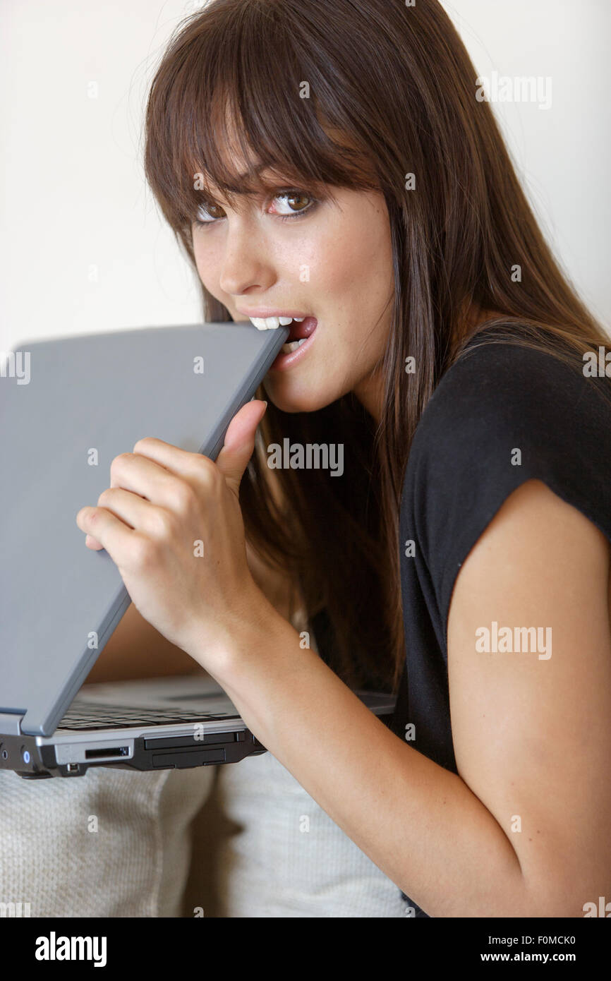 Young woman biting in Laptop computer Stock Photo - Alamy