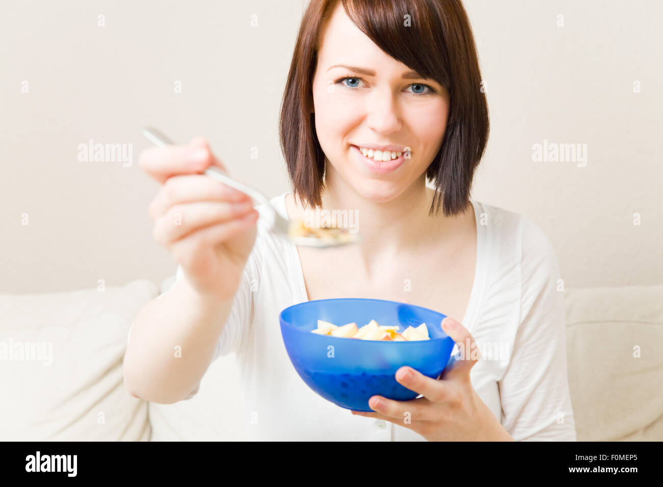 Young woman eating a bowl of muesli in her living room Stock Photo - Alamy