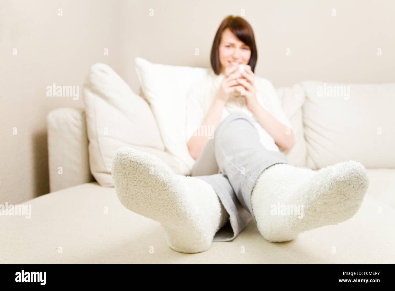 Young woman drinking hot coffee and resting her feet Stock Photo - Alamy