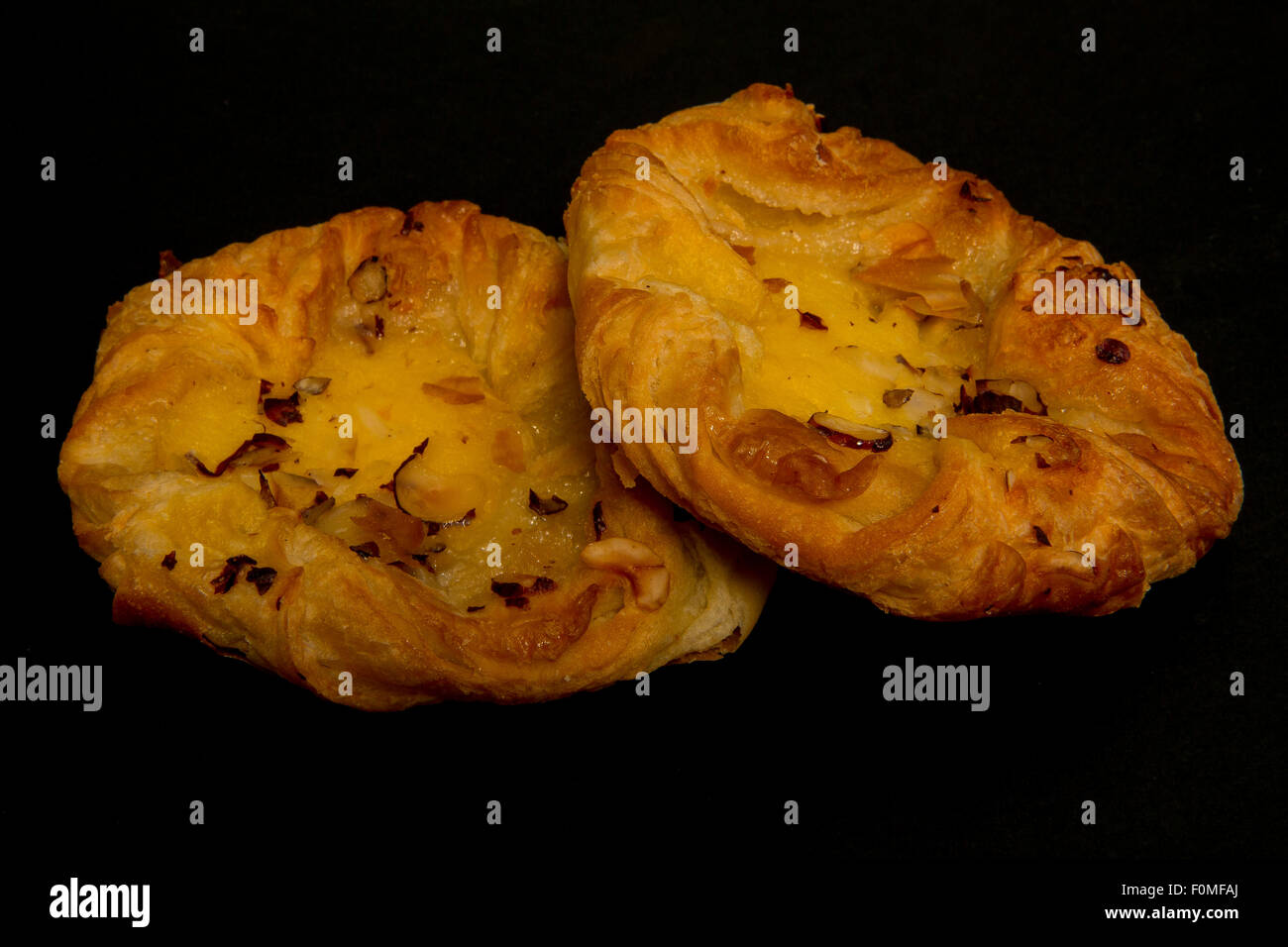 Still life of two Vanilla Crown pastries against a black background ...