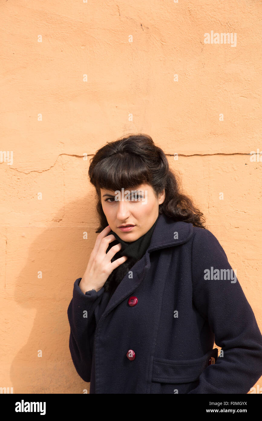 A retro styled girl waiting and leaning against a wall Stock Photo - Alamy