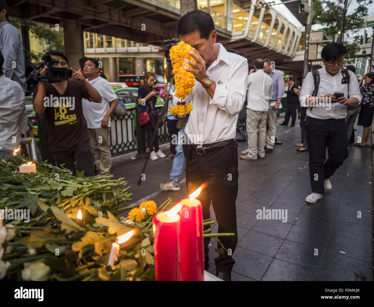 Bangkok, Thailand. 18th Aug, 2015. A man brings a marigold garland to a ...
