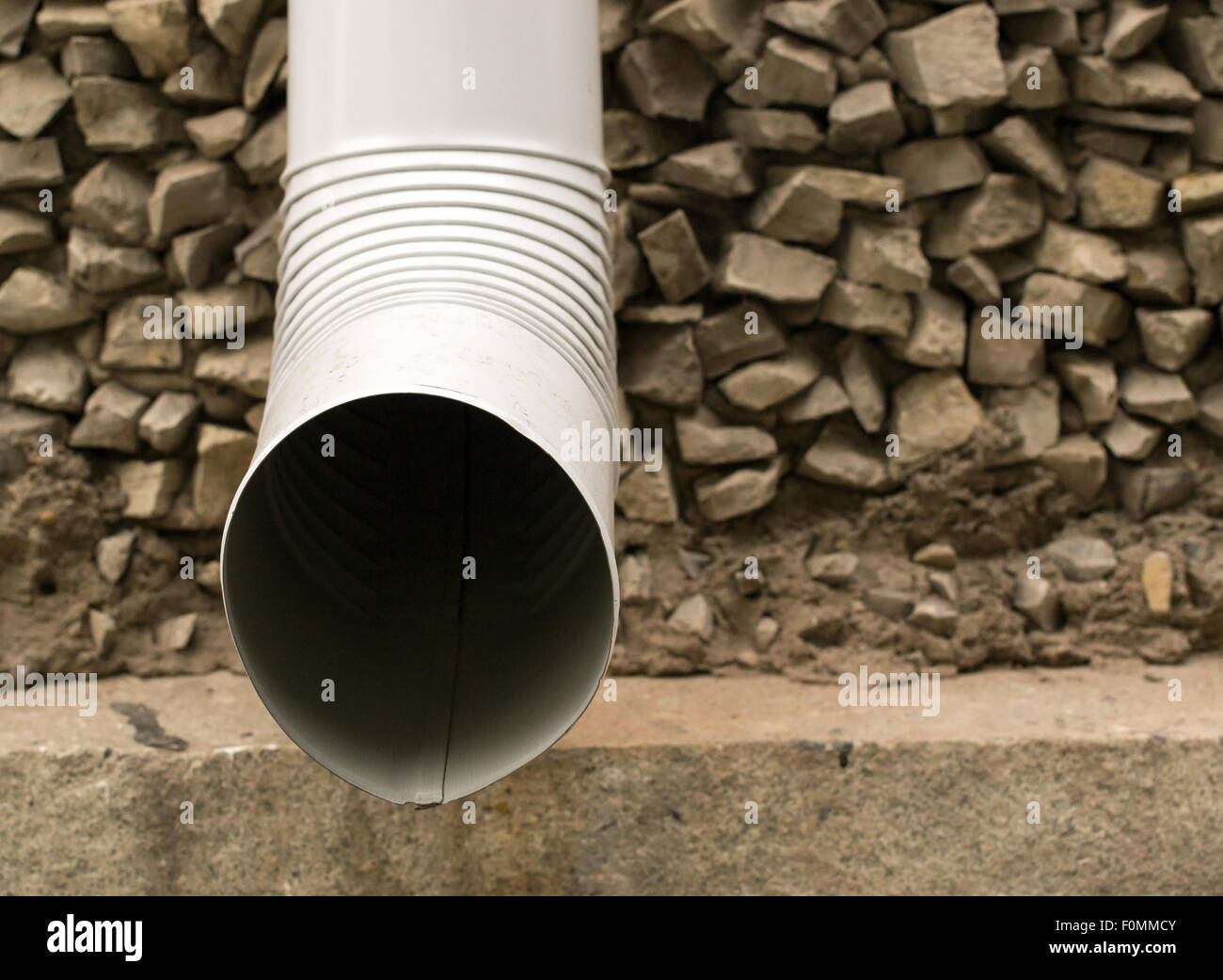 Industrial Water Drain pipe with rock wall background Stock Photo - Alamy