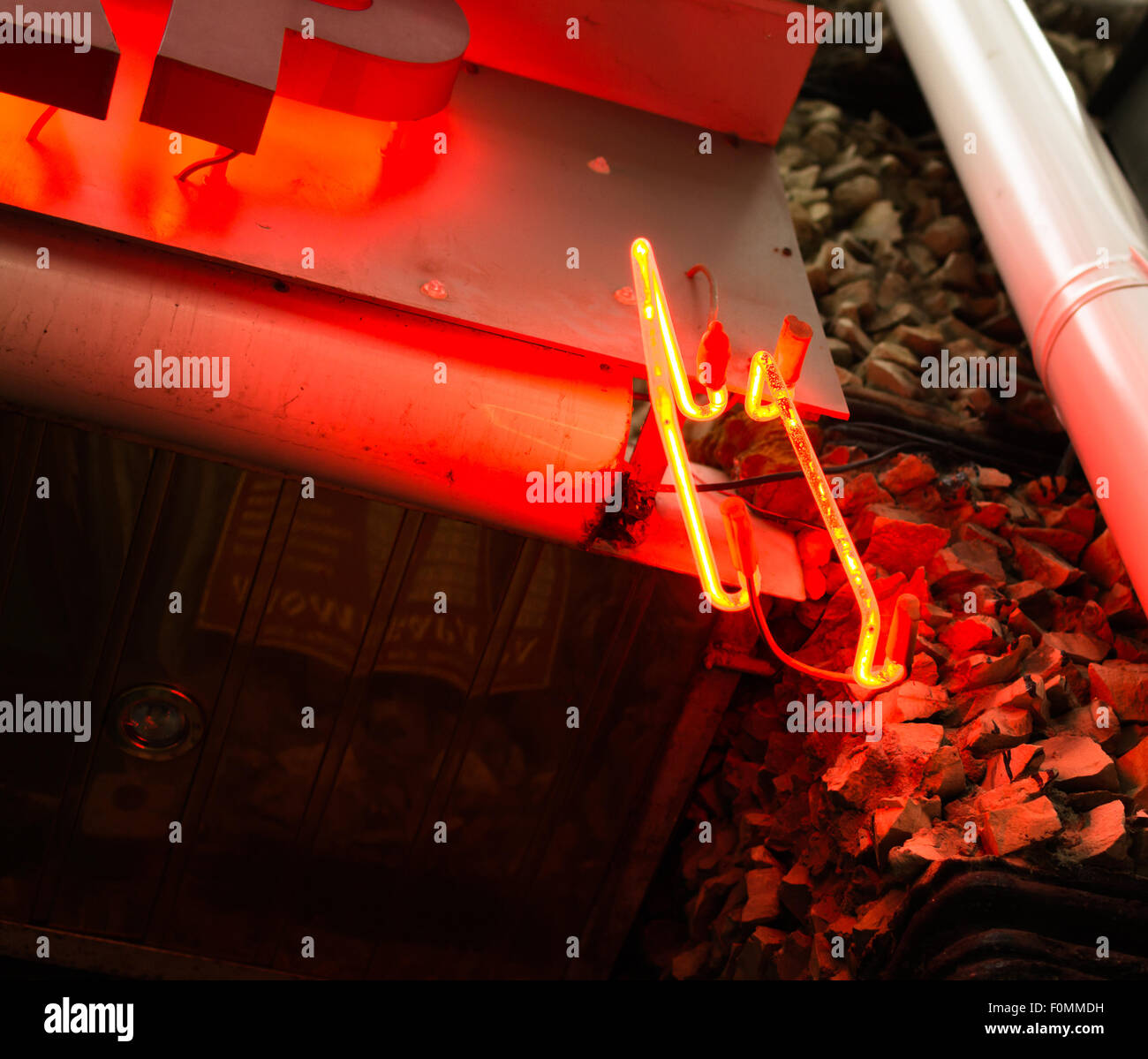 Broken red neon sign hanging from a display against a brick wall Stock ...