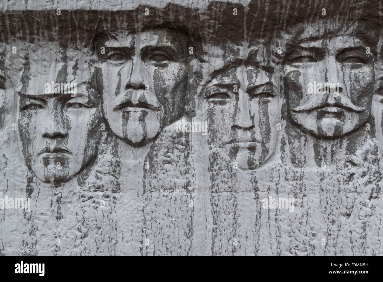 Stone carved faces on white marble rock with signs of aging Stock Photo ...