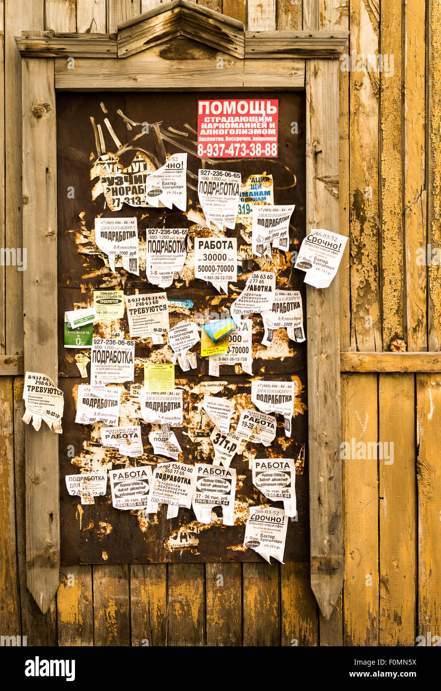 Old style posters ripped and torn on a metal billboard with wood edging ...