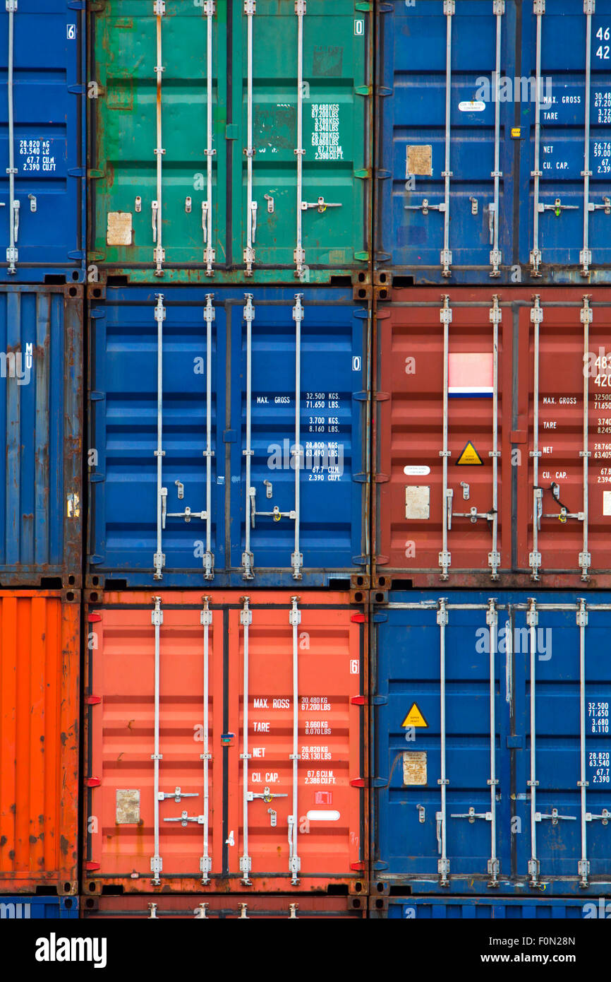 Three vertical rows of shipping containers that are different colours ...