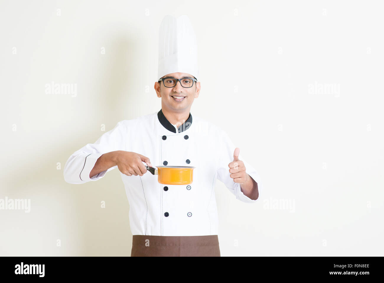 Portrait of handsome Indian male chef in uniform cooking food and thumb ...