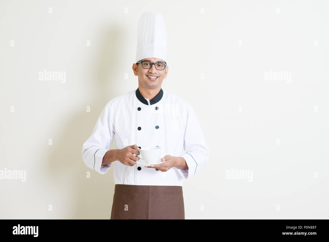Portrait of handsome Indian male chef in uniform holding coffee cup ...