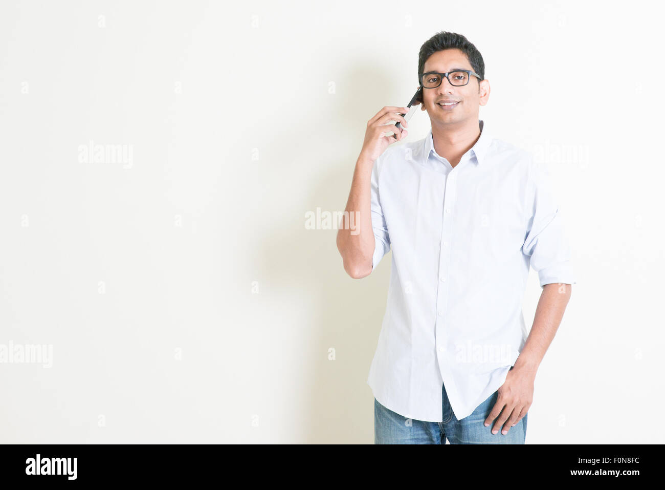 Portrait of handsome casual business Indian man using smartphone ...