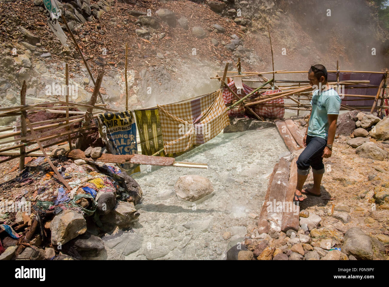 A visitor standing in front of a hot spring at the foot of Mount ...